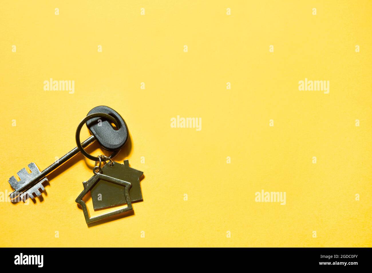 Key chain in the shape of wooden house with key on a yellow background ...