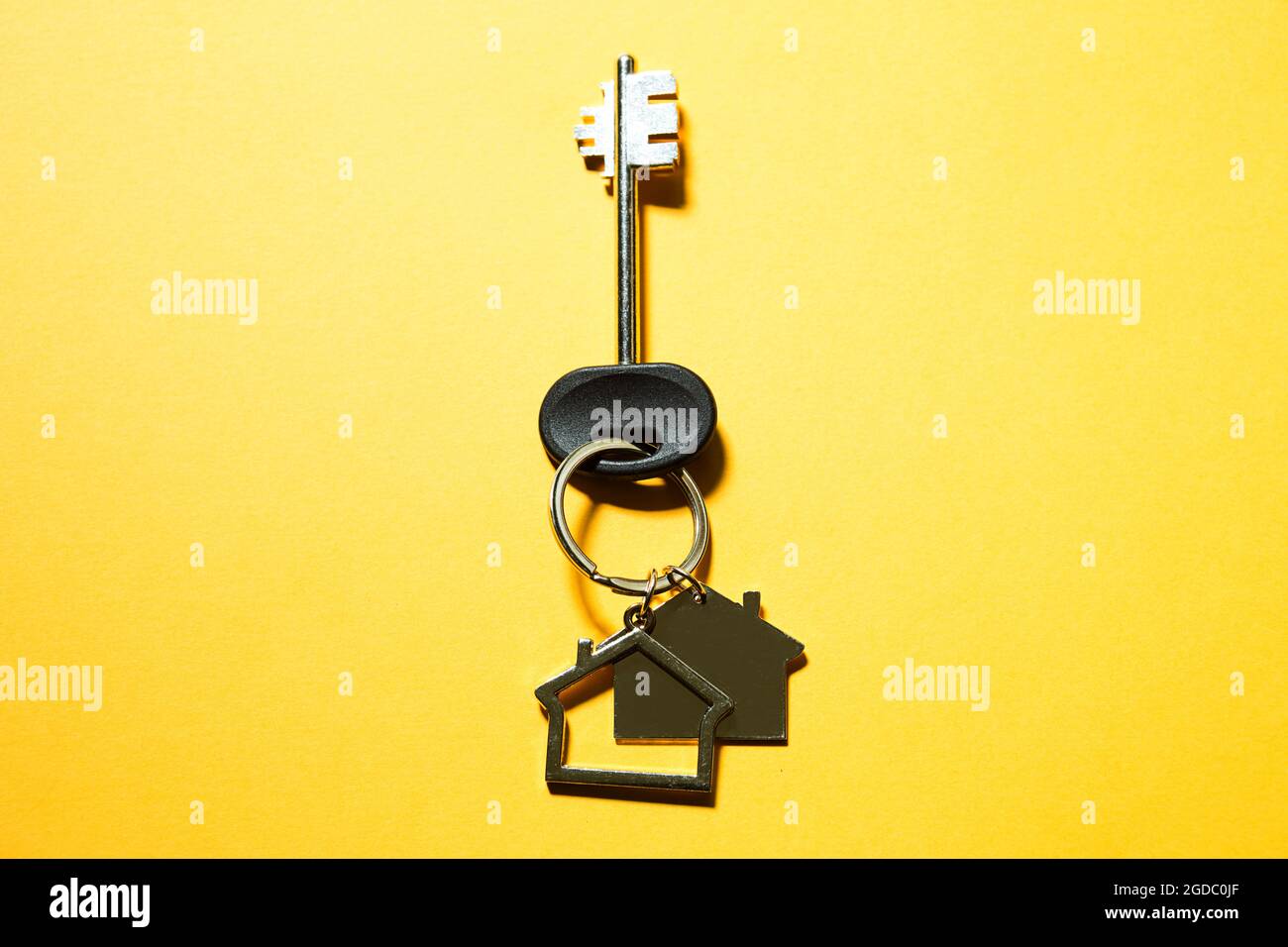 Key chain in the shape of wooden house with key on a yellow background ...