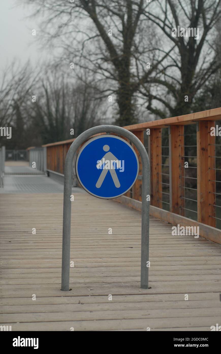 Vertical shot of a sign for pedestrians standing on a wooden surface ...
