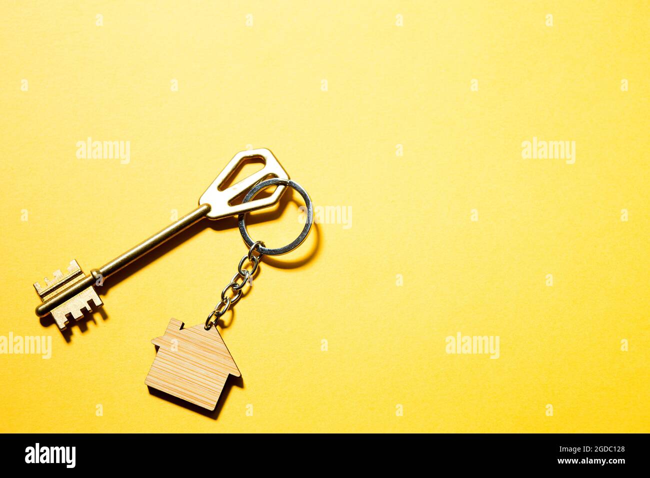 Key chain in the shape of wooden house with key on a yellow background ...