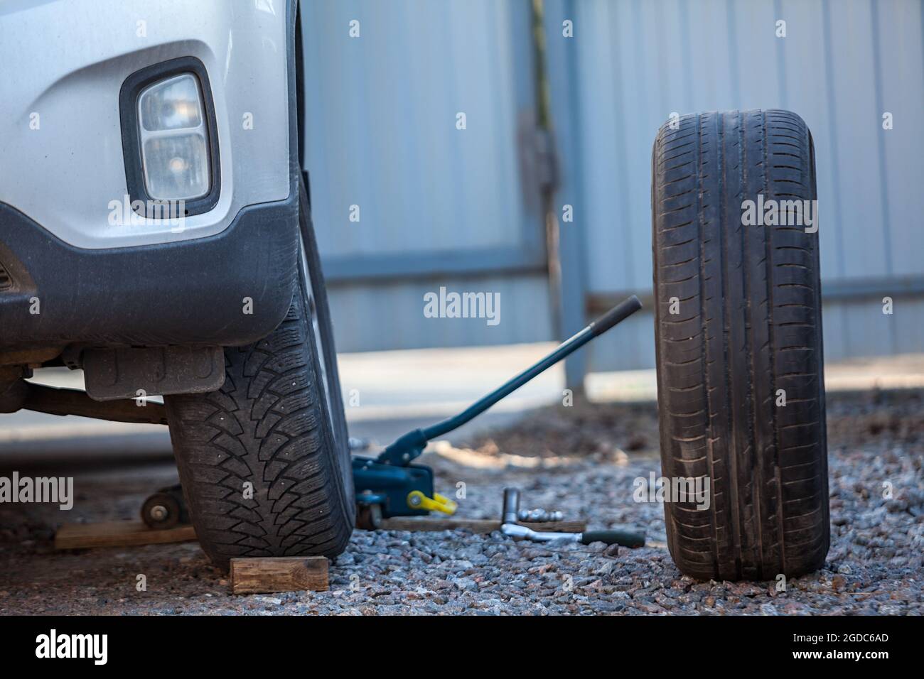 Car standing on a jack-screw for snow tire removing, summer wheel is ...