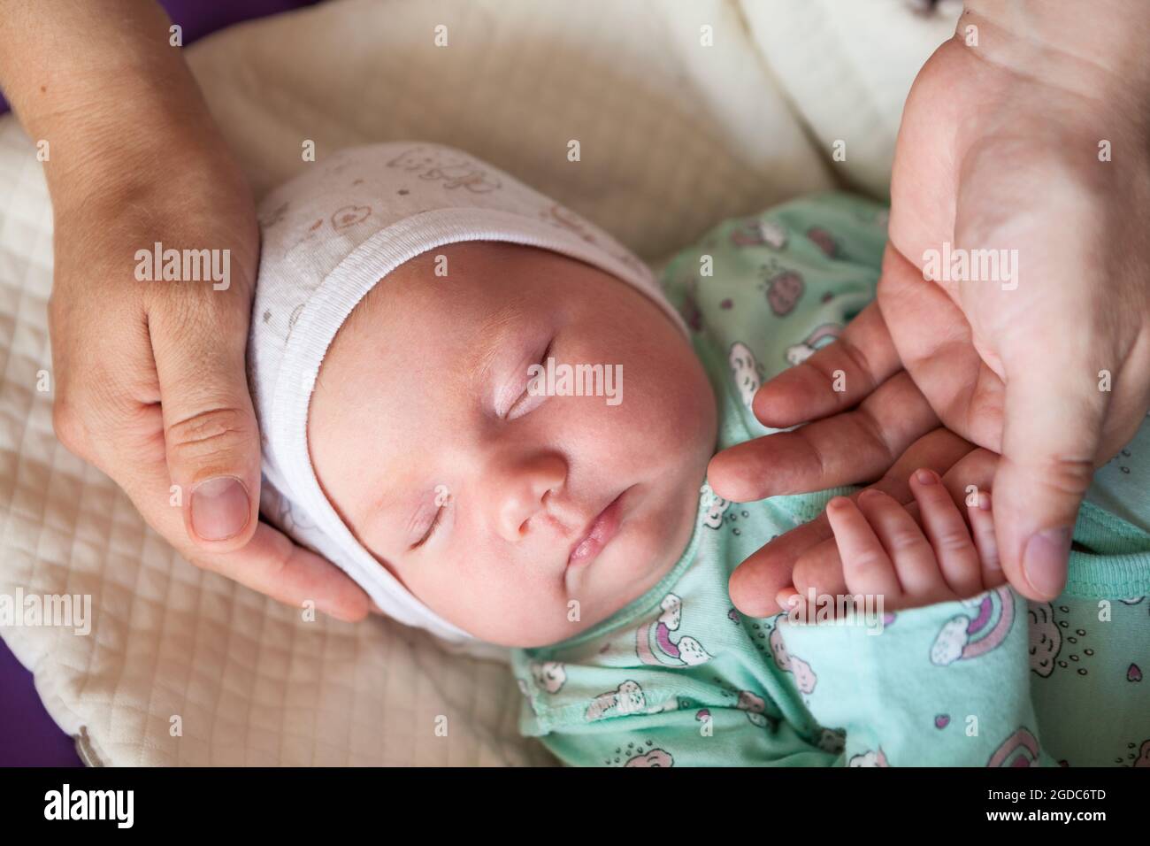 Close up view at sleeping Caucasian baby face with mother arms around ...