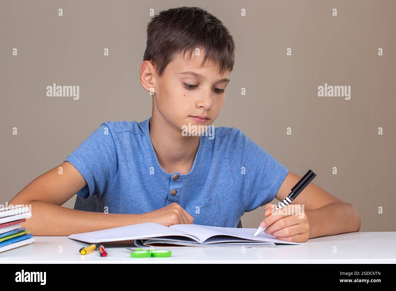 Boy hand holding pen in left hand and writing in a notebook, doing ...