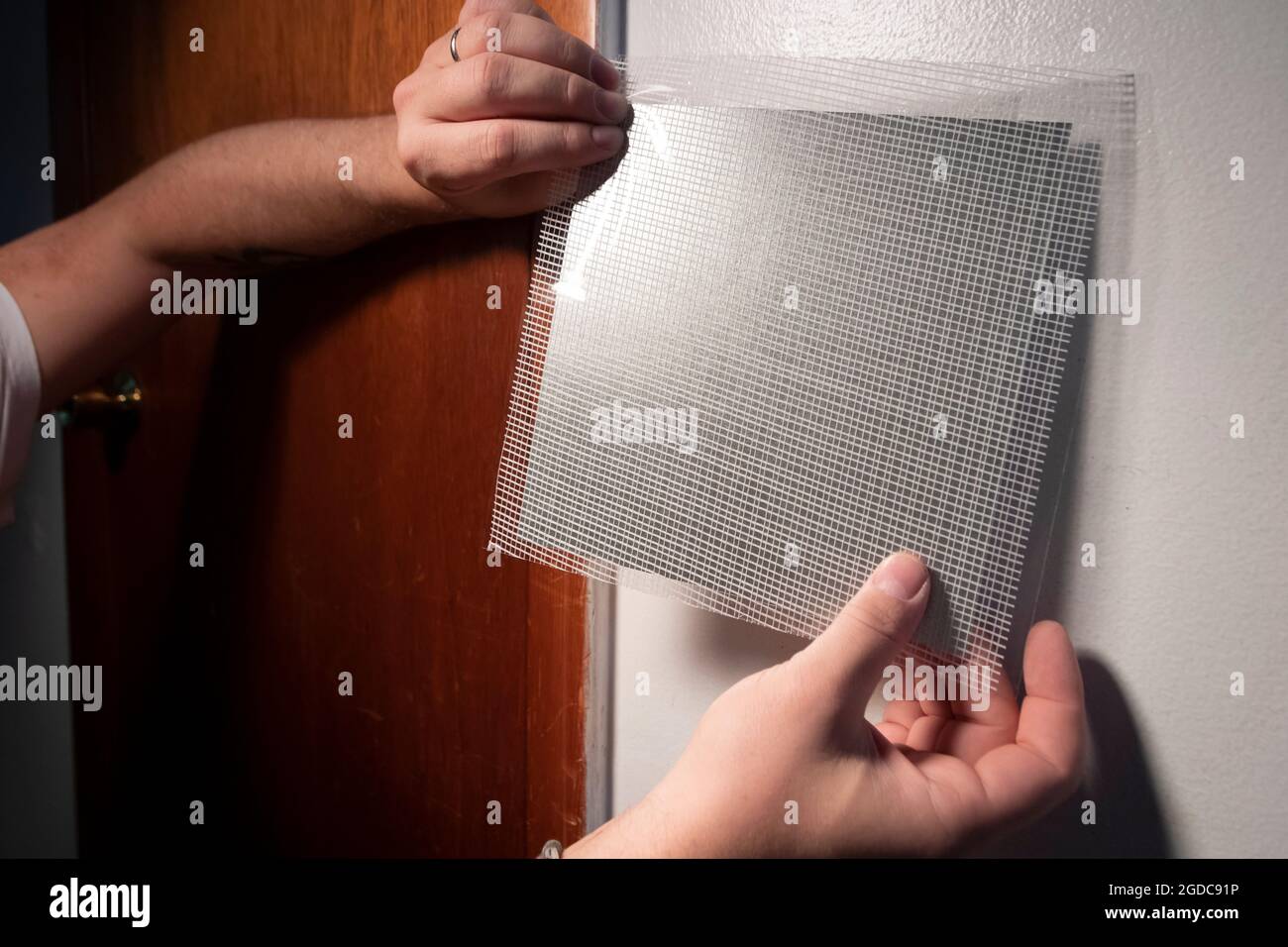 Sizing up metal and mesh patch to place over damaged drywall hole Stock ...