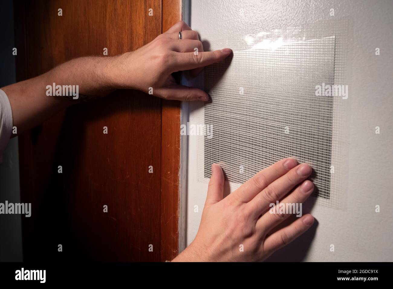 Application of metal and mesh patch over damaged drywall hole Stock ...