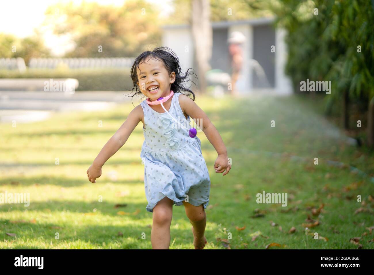 Cute Asian female child running on a meadow Stock Photo - Alamy