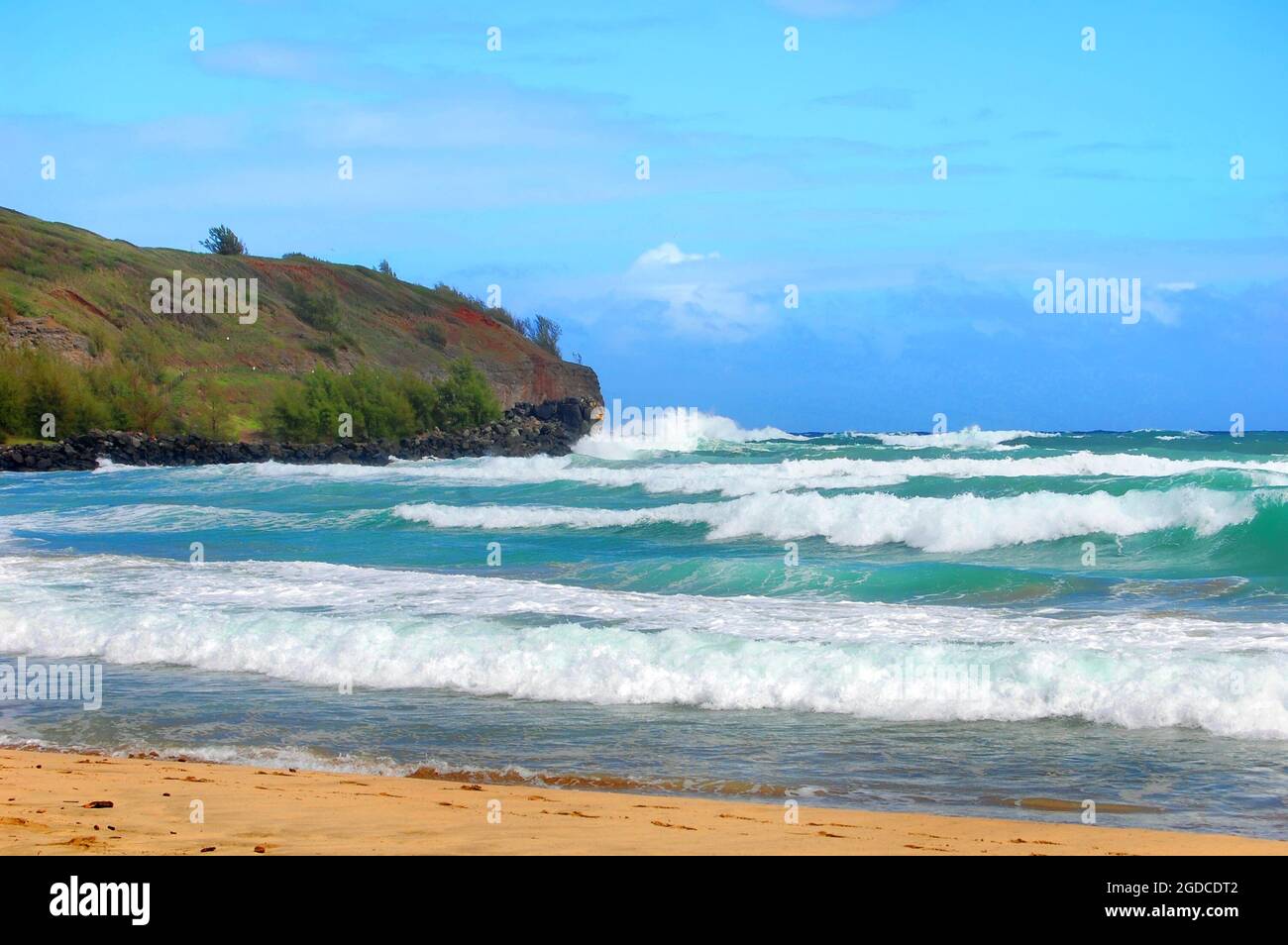 Deserted beach on the Island of Kauai, Hawaii has rocky outcrop and ...