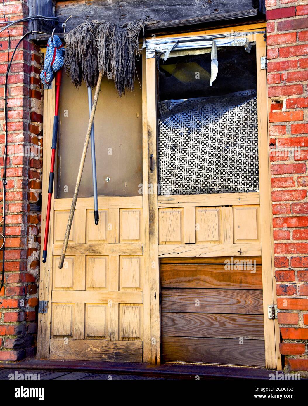 Alley reveals grungy back door with three hanging mops. Metal grate ...