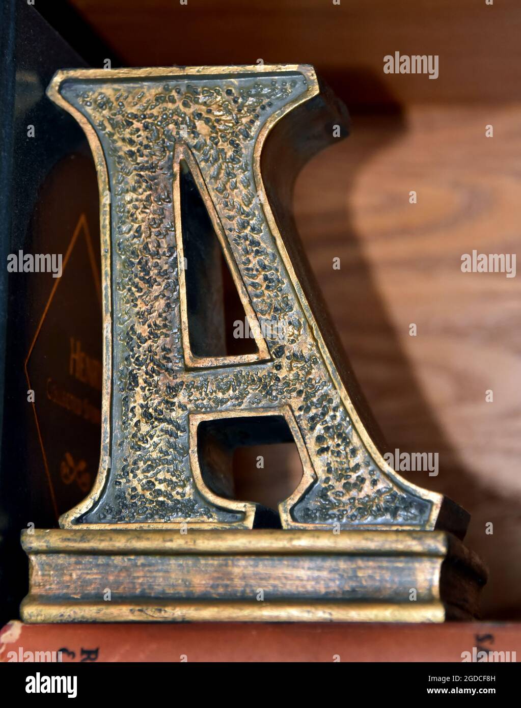 The letter "A" sits on a stack of books in a library. It is made of ...