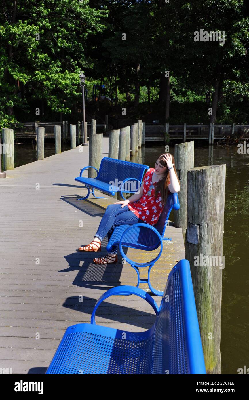 Attractive woman sits on the pier at Dunton Park in Holland, Michigan ...