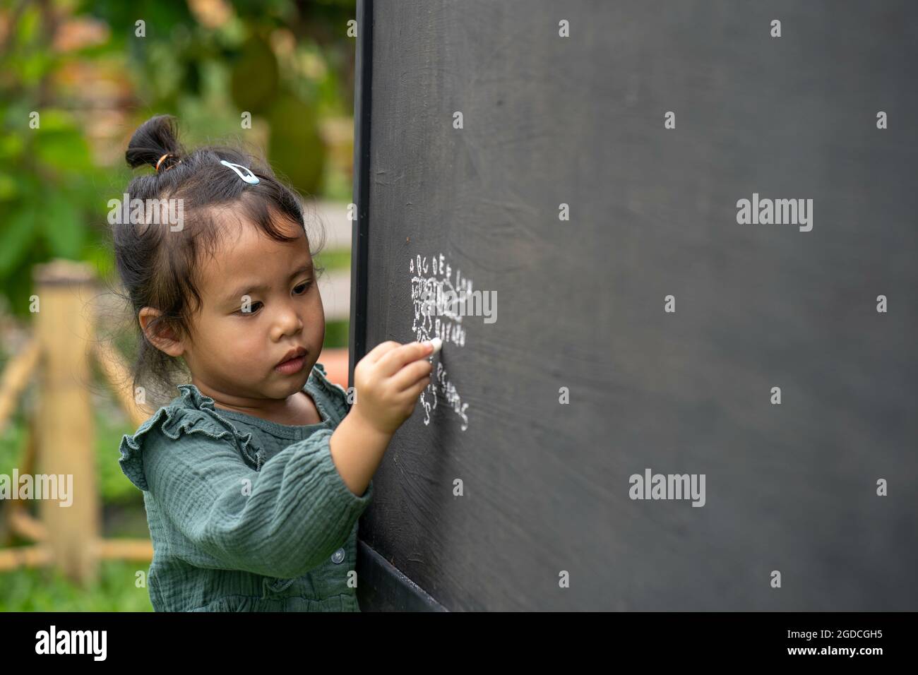 Closeup shot of a female kid writing on a blackboard in nature Stock ...