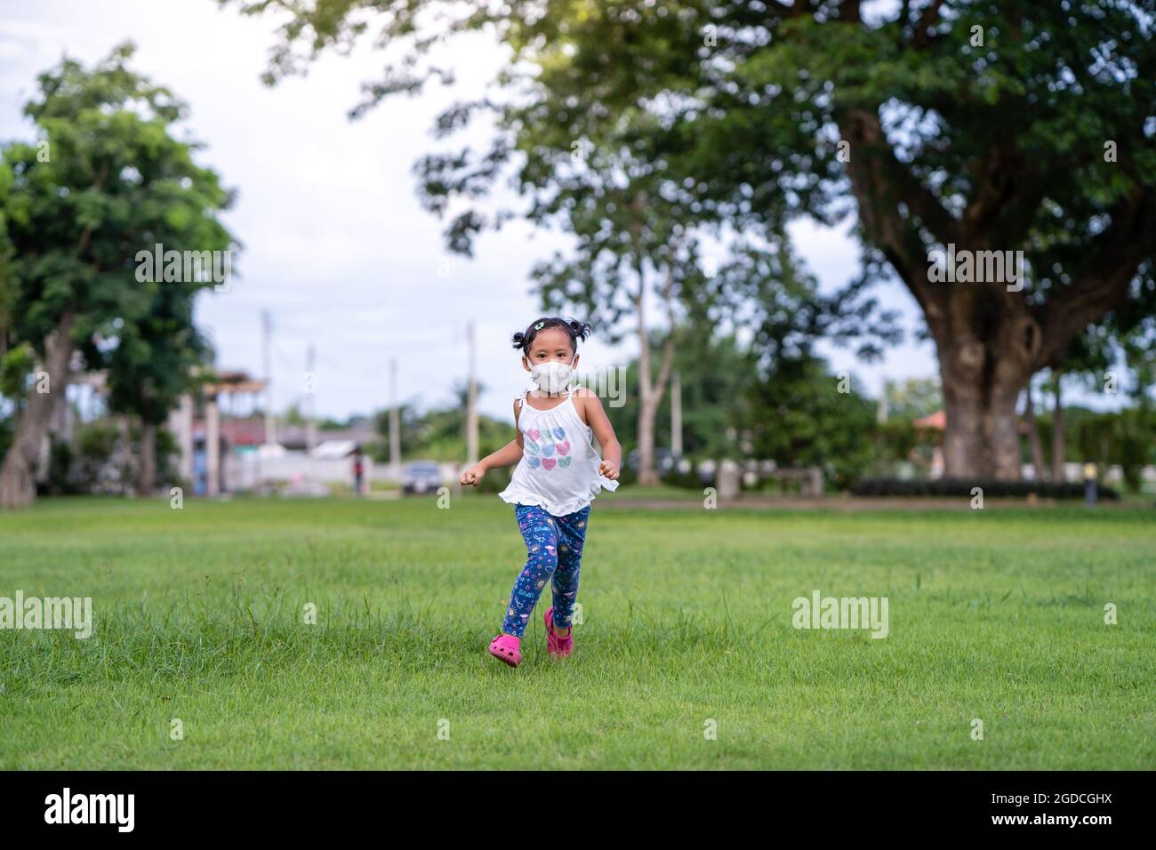 Beautiful southeast Asian female kid running on a lawn Stock Photo - Alamy