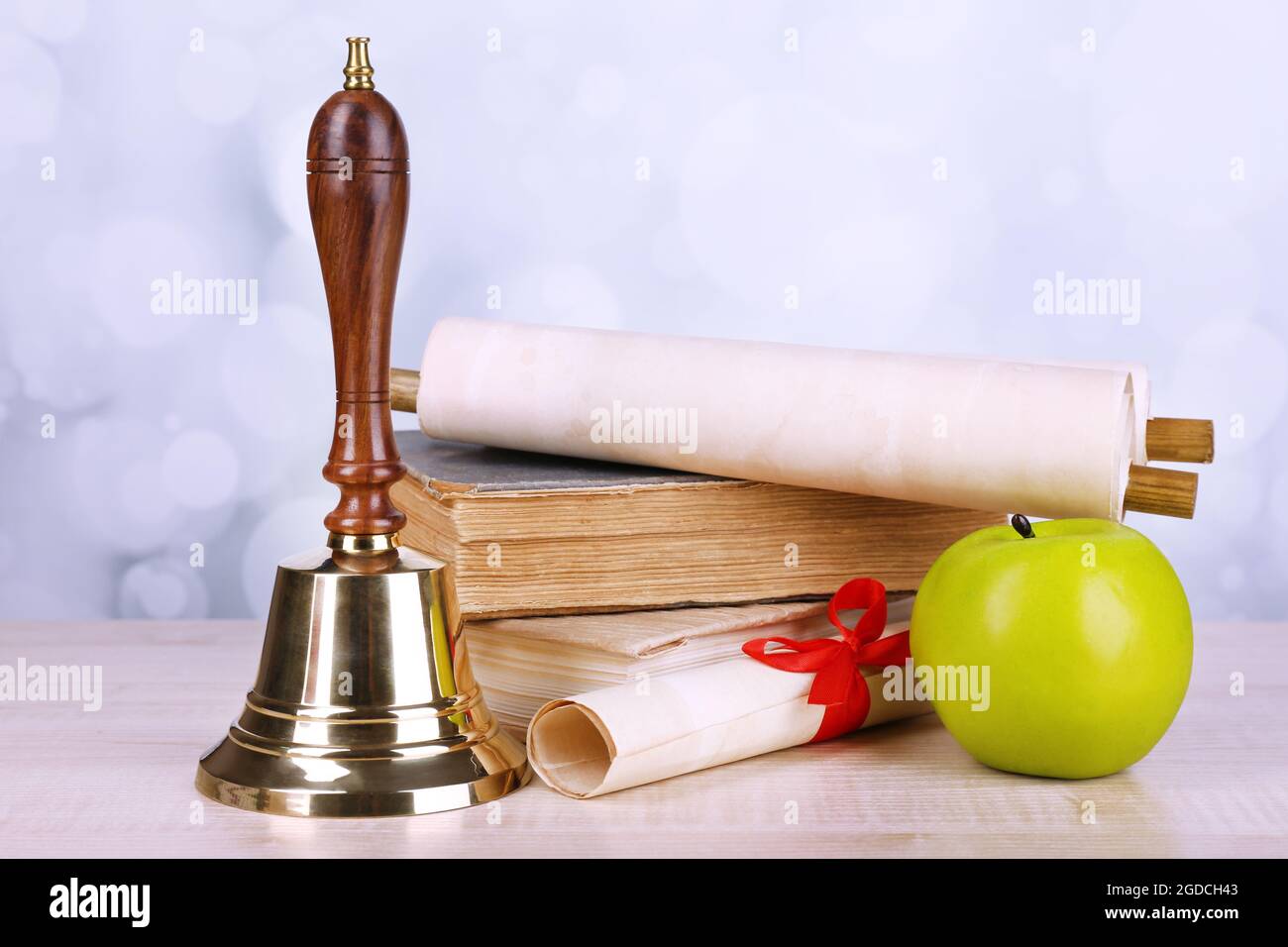 Gold school bell with school supplies on table on bright background ...
