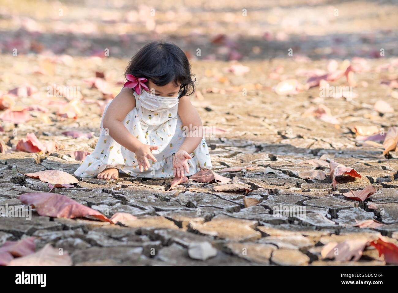 Southeast Asian female kid sitting on the textured ground and playing ...