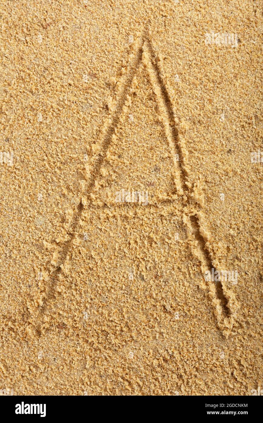 Alphabet letter written on wet beach sand Stock Photo - Alamy