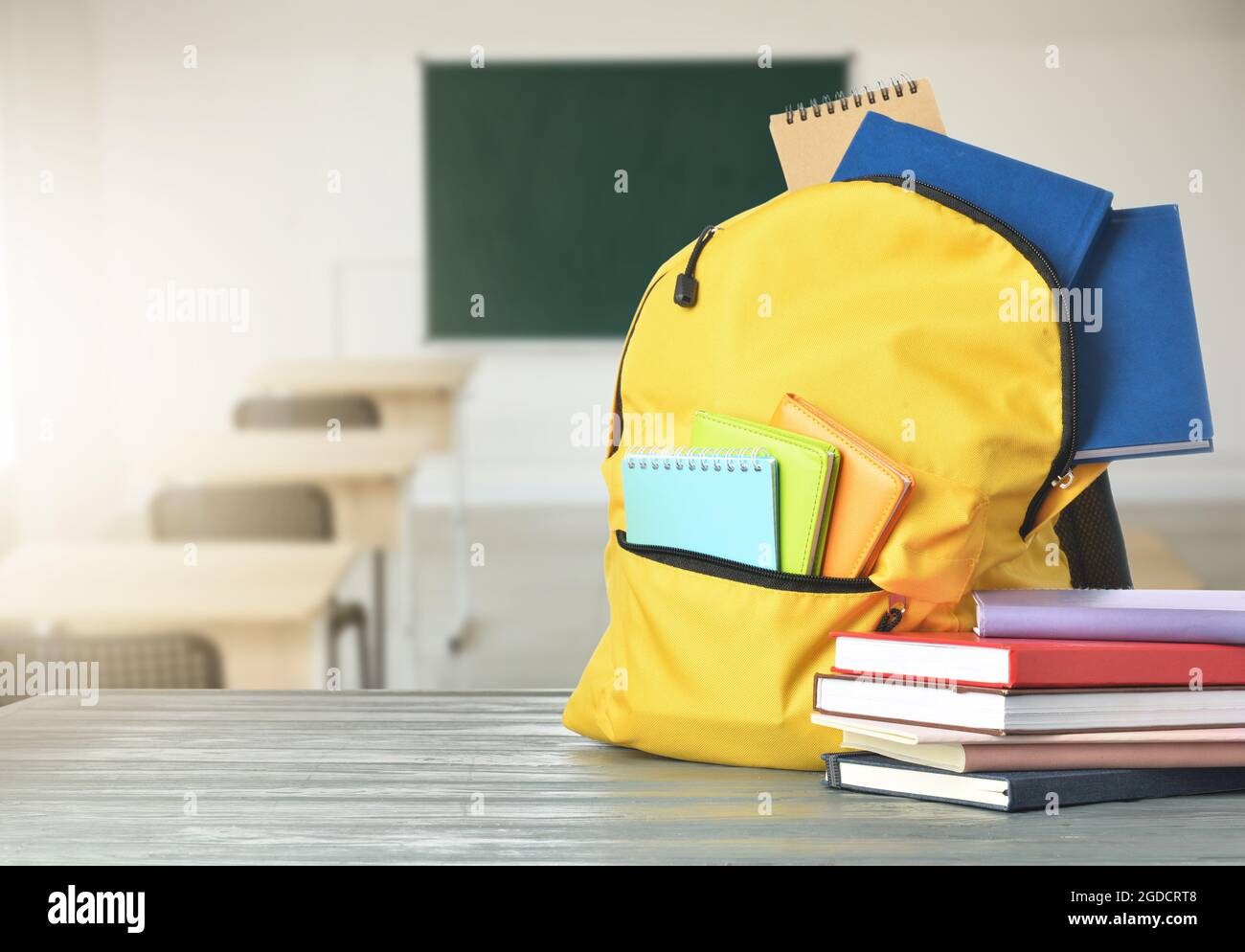School backpack with books on desk in classroom Stock Photo - Alamy