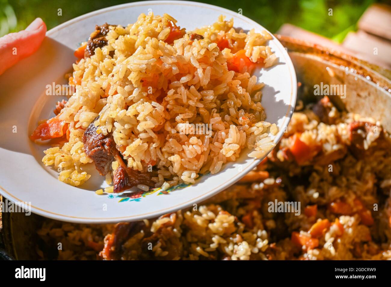 Traditional oriental pilaf in a cauldron on a sunny day. Step-by-step ...
