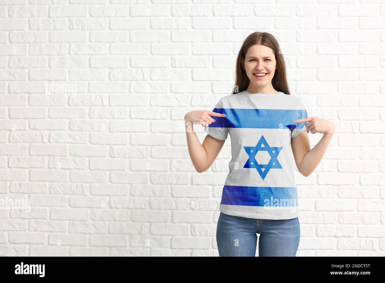 Young woman in t-shirt with Israeli flag on white brick background ...