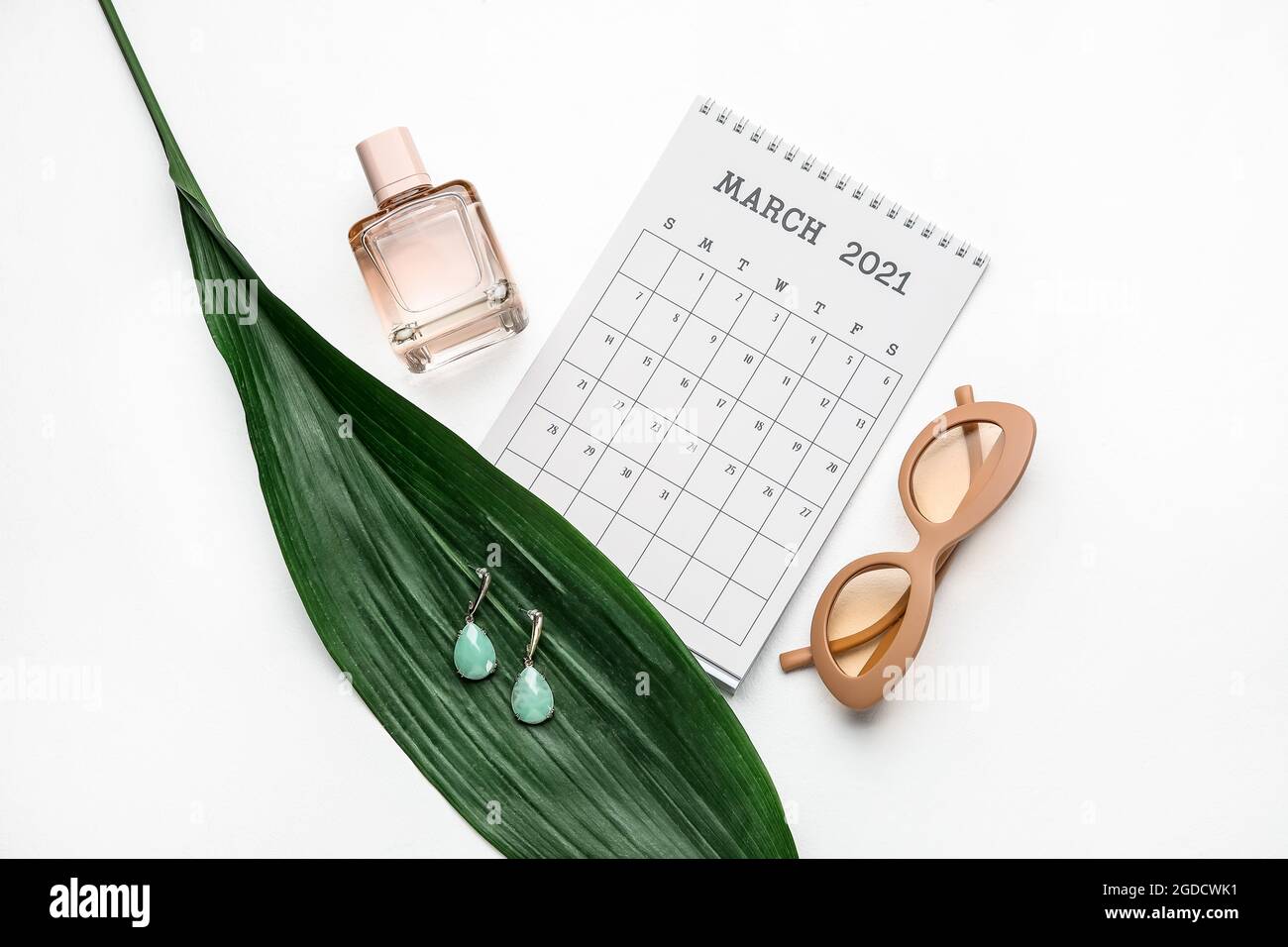 Calendar with female accessories and tropical leaf on white background ...