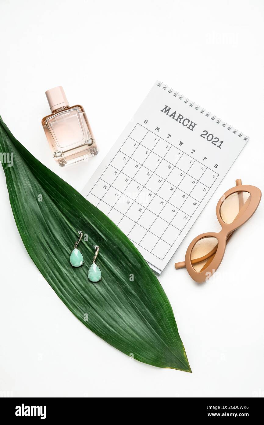 Calendar with female accessories and tropical leaf on white background ...