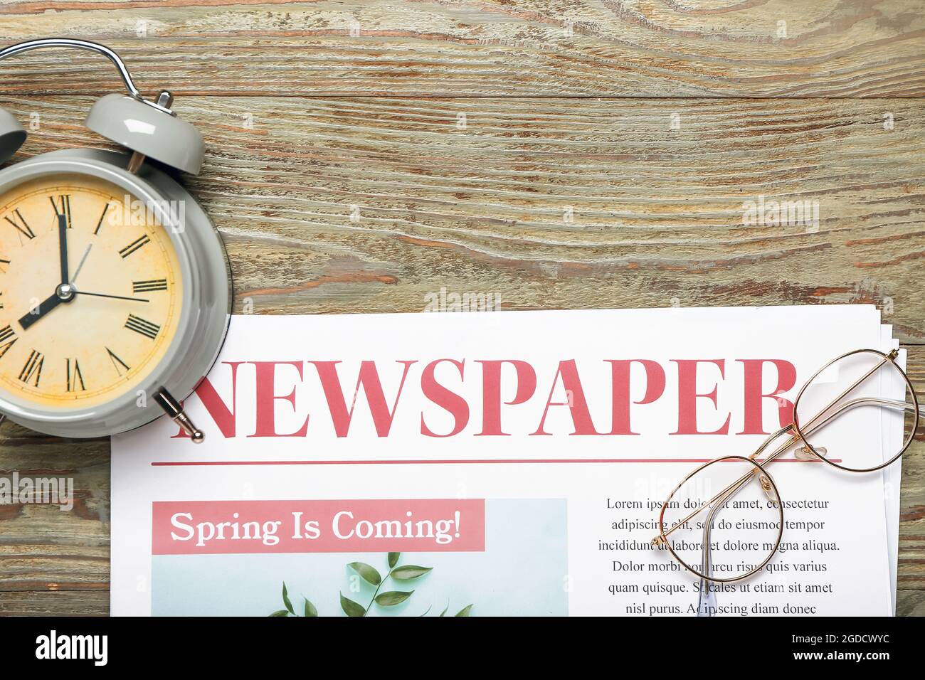 Newspaper with alarm clock and eyeglasses on wooden background, closeup ...