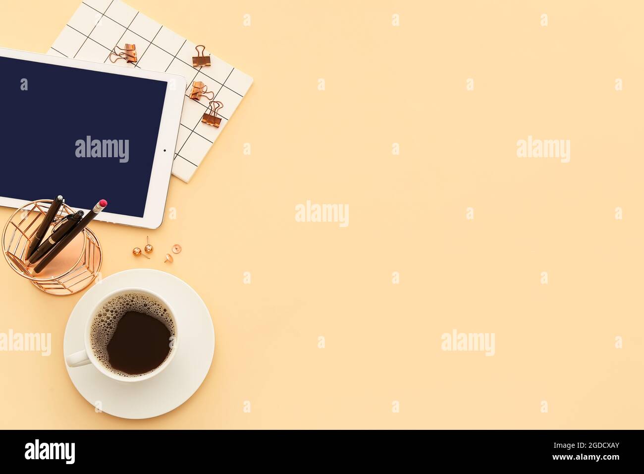 Tablet computer with stationery and cup of coffee on color background ...