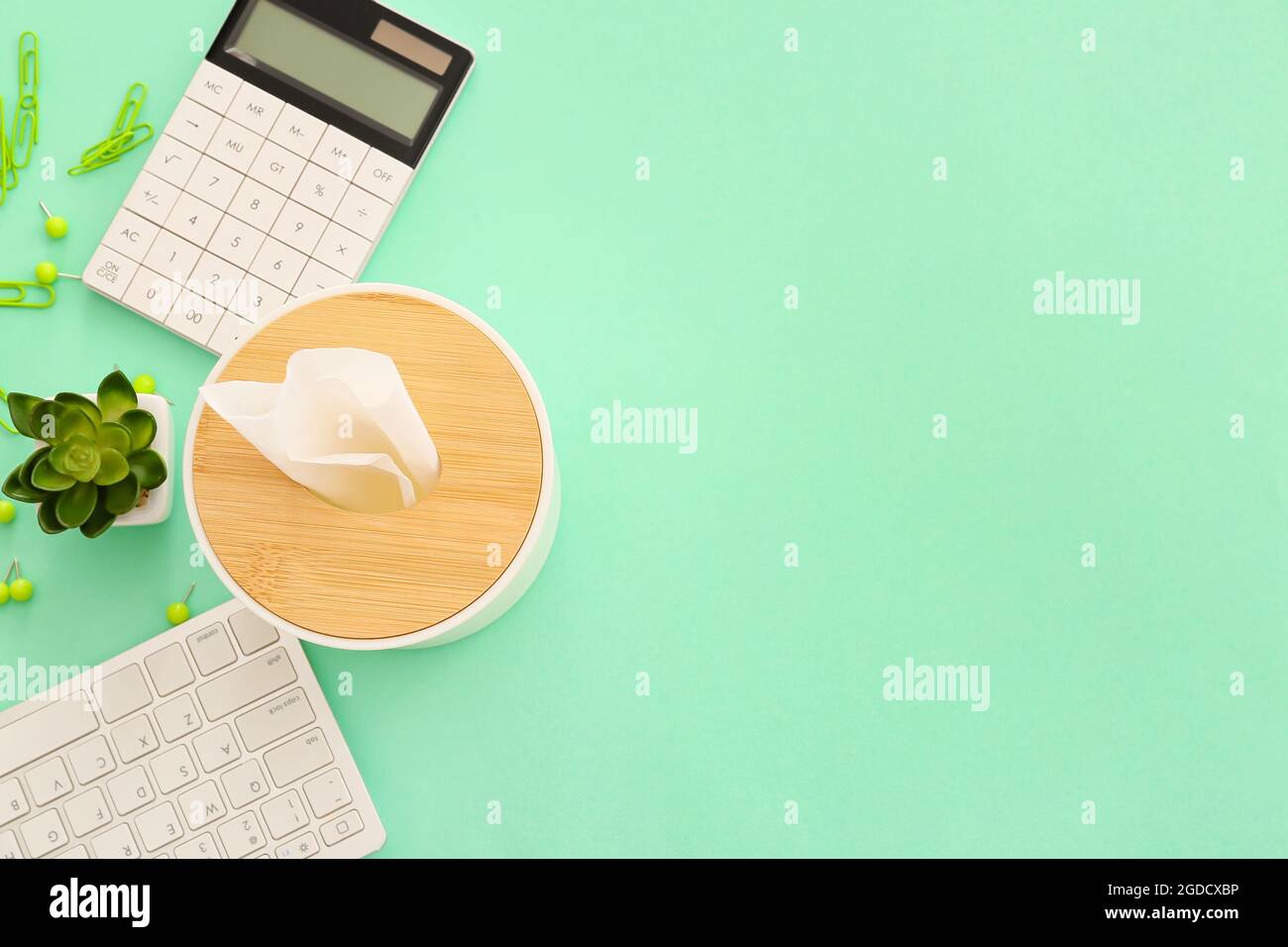 Computer keyboard with stationery and tissue box on color background ...