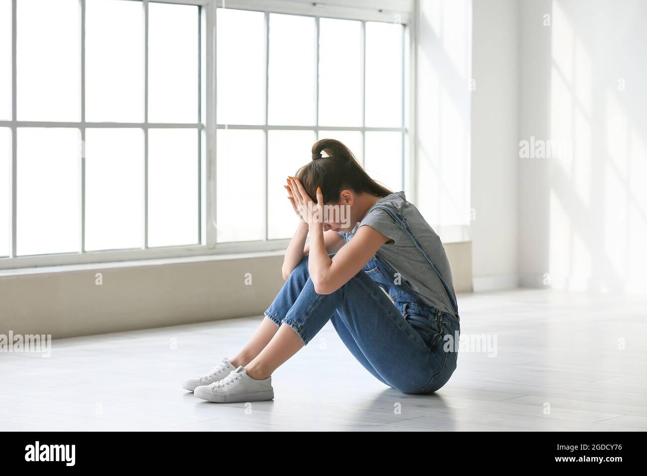 Depressed young woman in empty room Stock Photo - Alamy