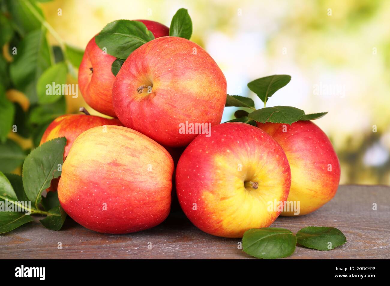 Ripe sweet apples with leaves on nature background Stock Photo - Alamy