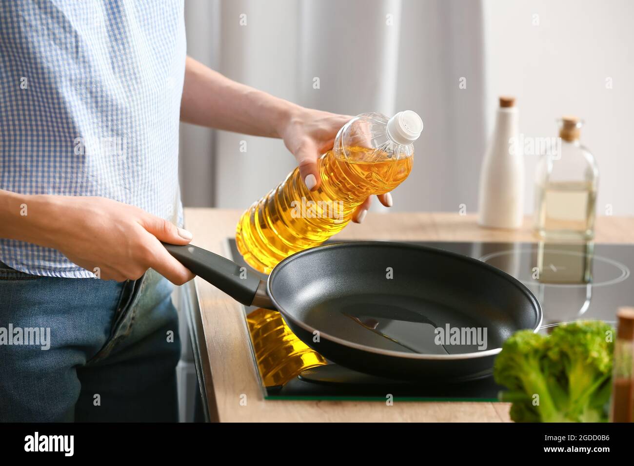 Young woman pouring oil into frying pan in kitchen Stock Photo - Alamy