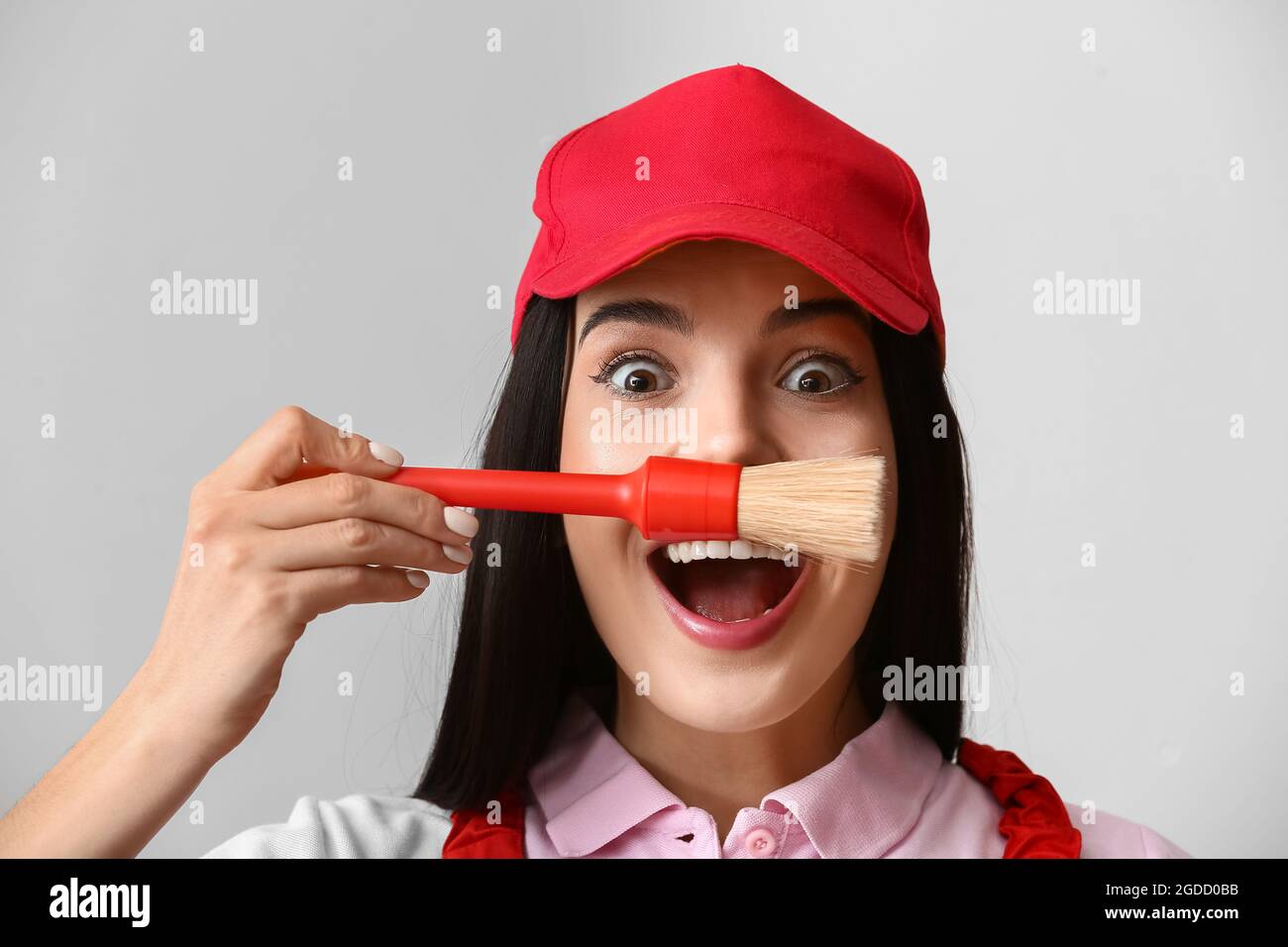 Funny female decorator with brush on light background Stock Photo - Alamy