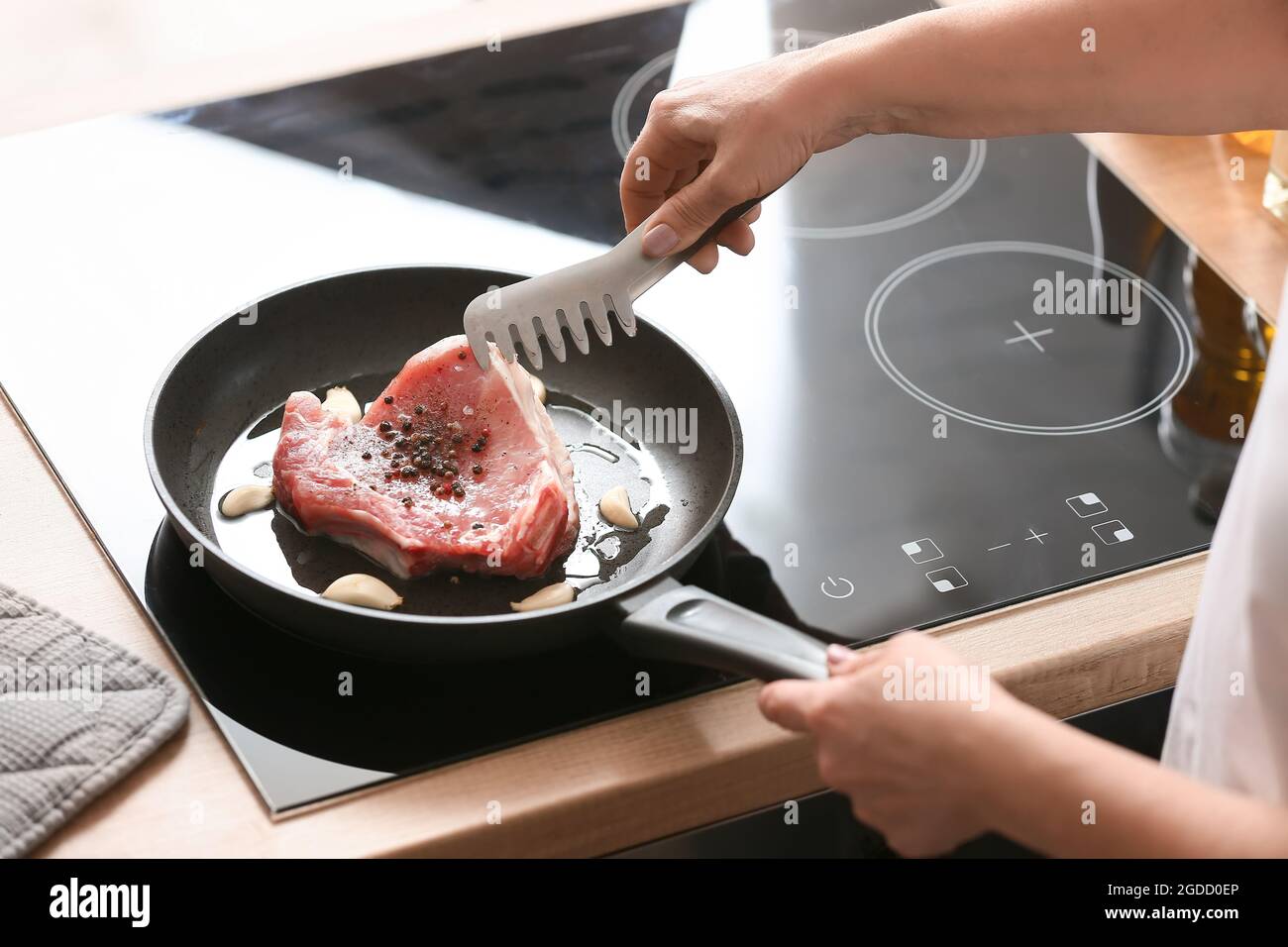 Mature woman frying meat in kitchen Stock Photo - Alamy