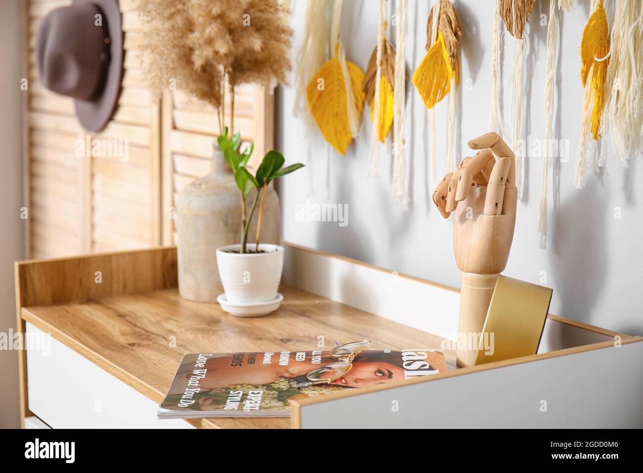 Wooden hand with magazine and decor on shelf near light wall Stock ...