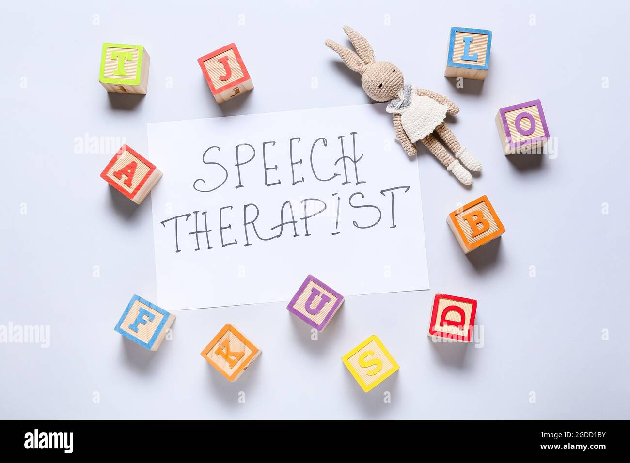 Paper with text SPEECH THERAPIST, toy and cubes on light background ...
