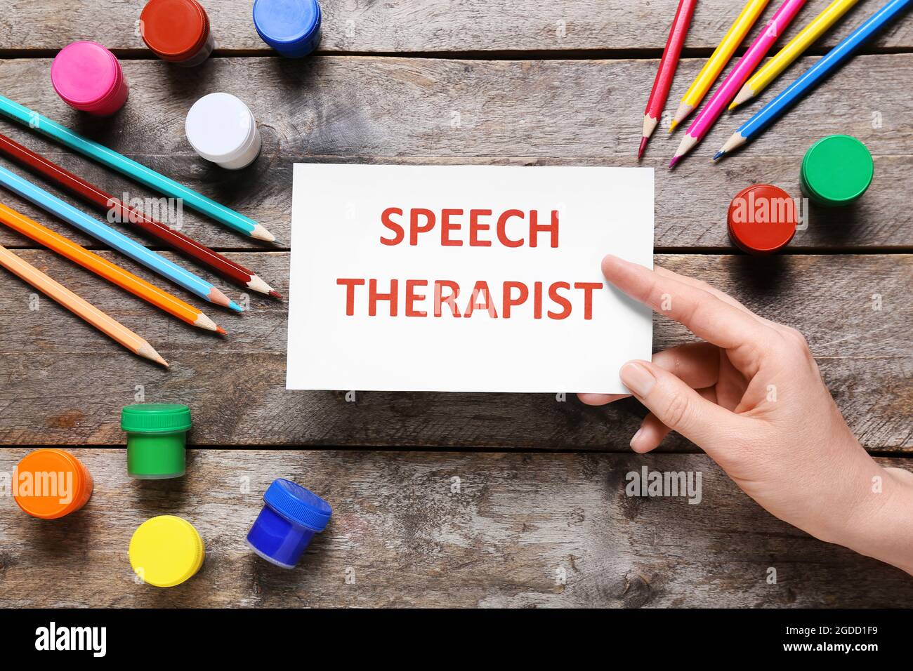 Woman holding paper with text SPEECH THERAPIST, paints and pencils on ...