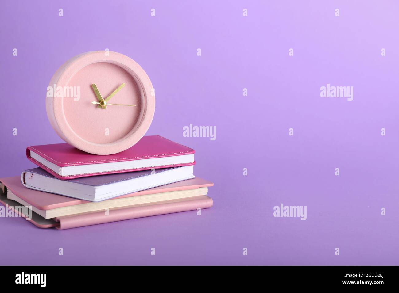 Stylish alarm clock with notebooks on color background Stock Photo - Alamy