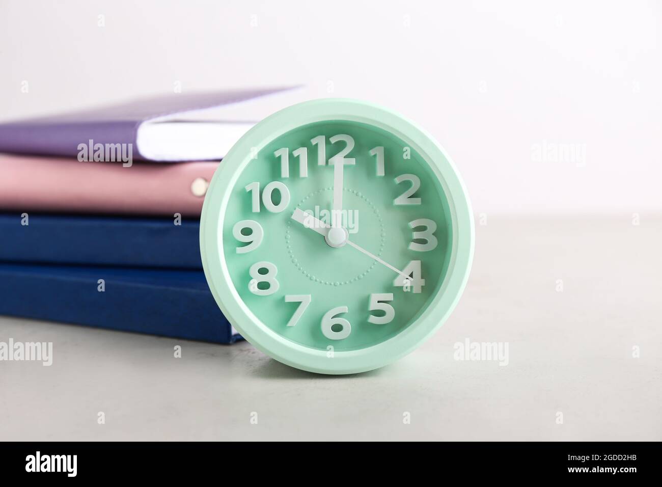 Stylish alarm clock with books on white background Stock Photo - Alamy