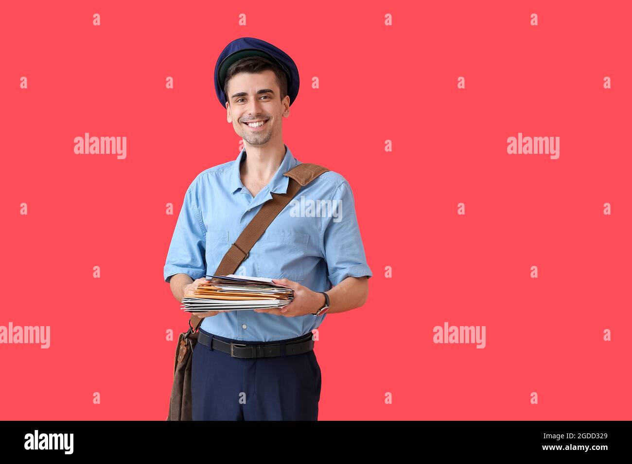 Handsome young postman on color background Stock Photo - Alamy
