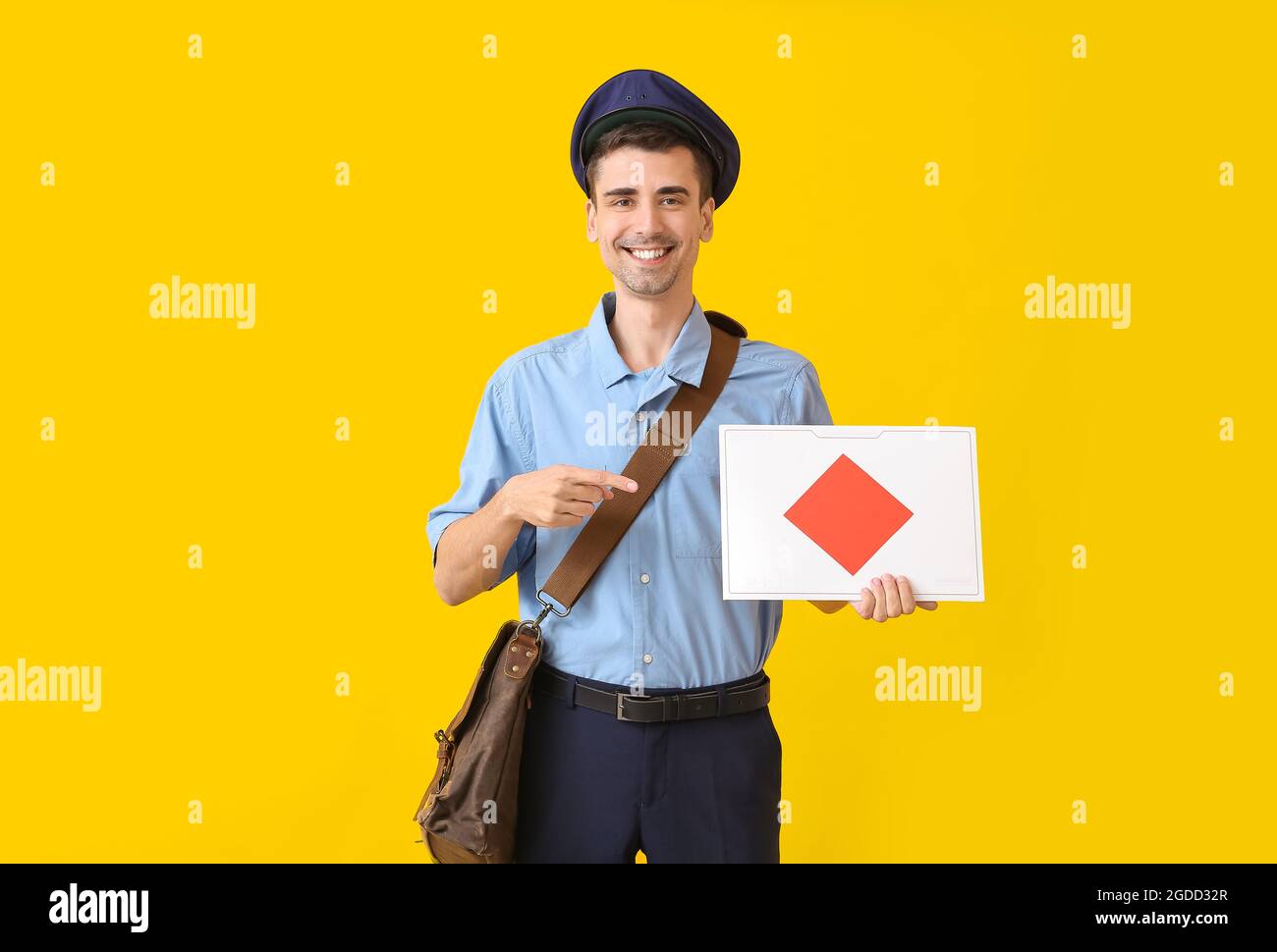 Handsome young postman pointing at letter on color background Stock ...