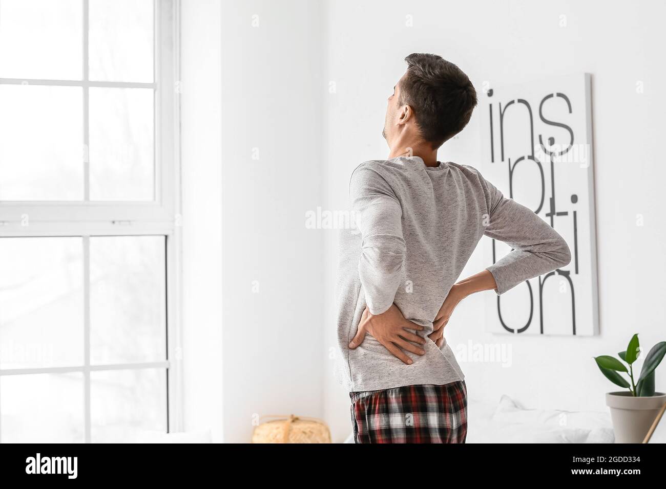 Young man suffering from back pain in bedroom Stock Photo - Alamy