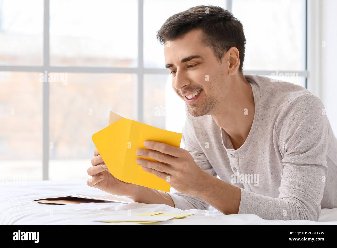 Young man reading letter in bedroom Stock Photo - Alamy