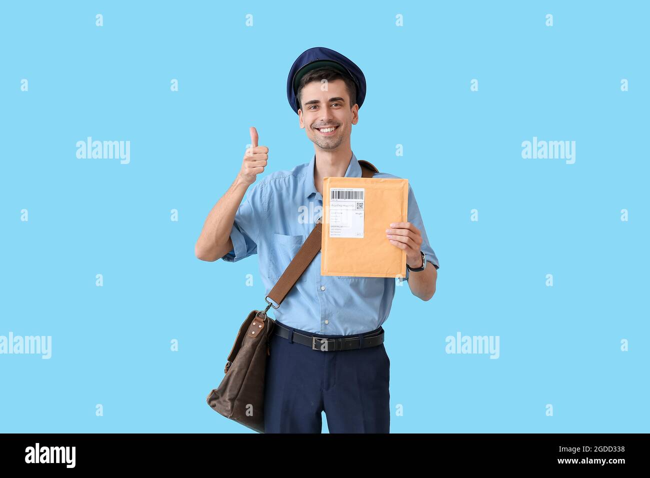 Handsome young postman with letter showing thumb-up on color background ...