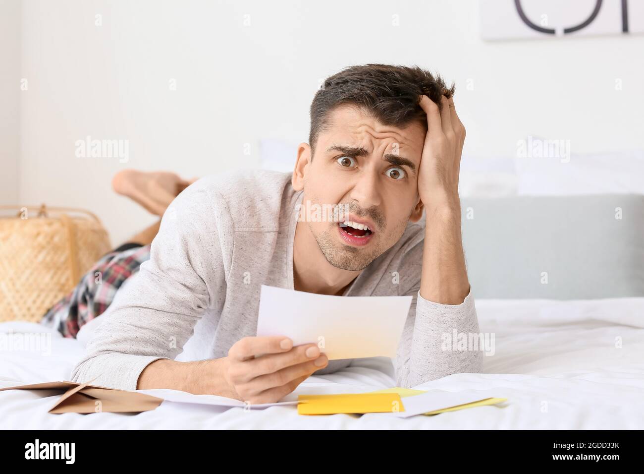 Shocked young man reading letter in bedroom Stock Photo - Alamy