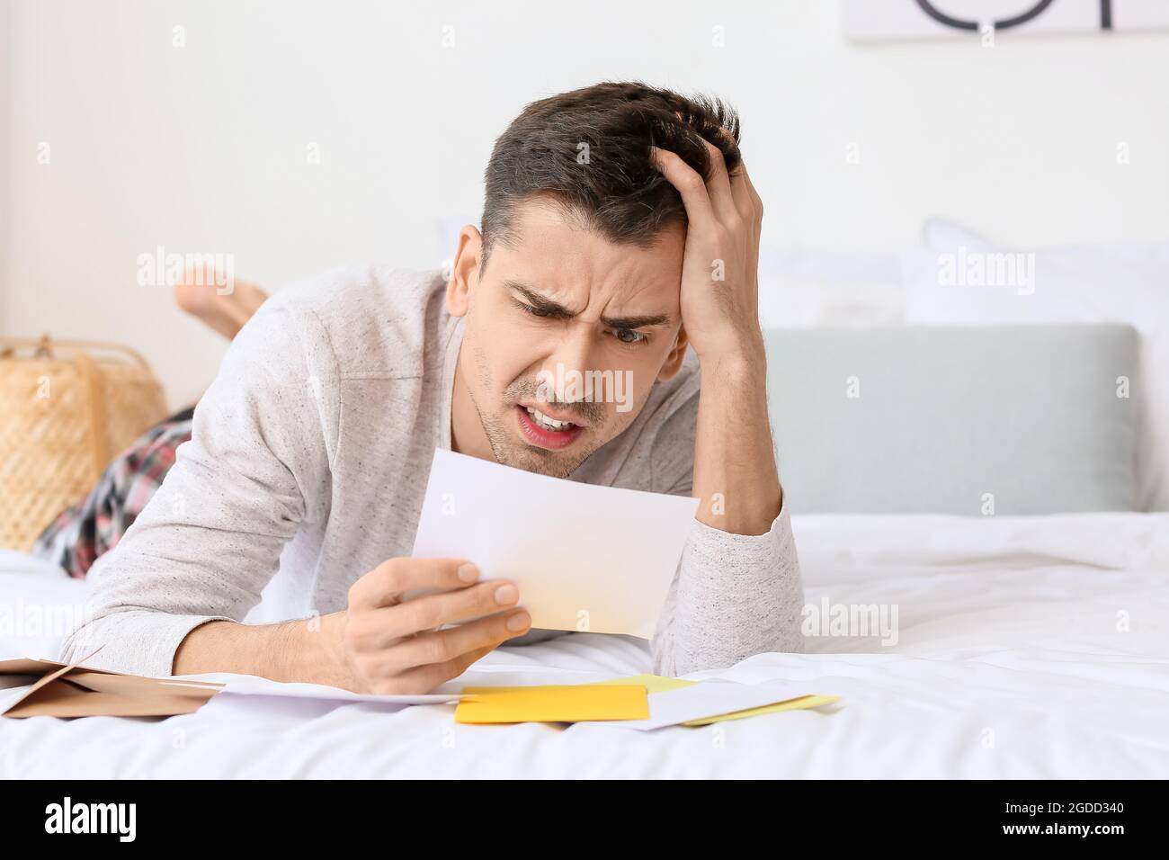 Shocked young man reading letter in bedroom Stock Photo - Alamy