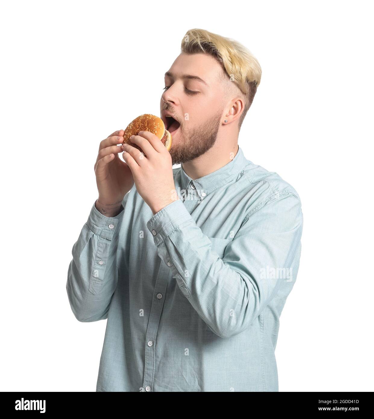 Young man eating vegan burger on white background Stock Photo - Alamy