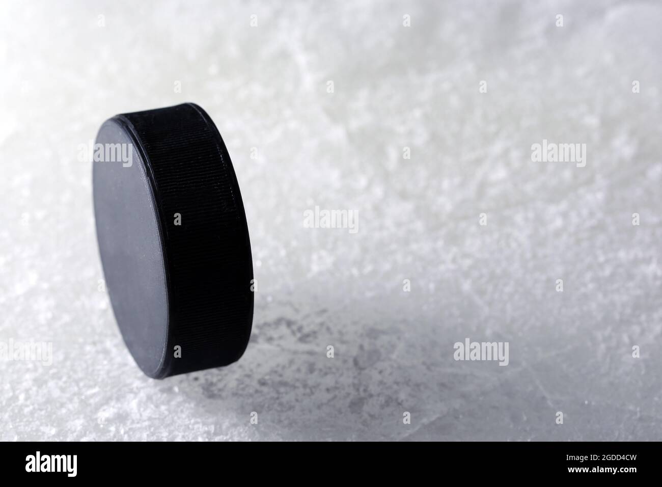 Black hockey puck on ice rink background Stock Photo - Alamy
