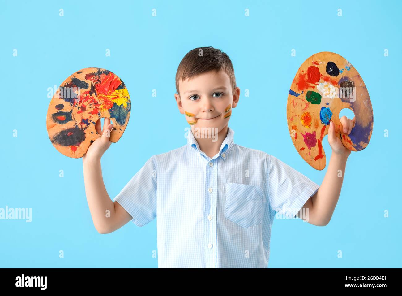 Cute little boy with paint palettes on color background Stock Photo - Alamy
