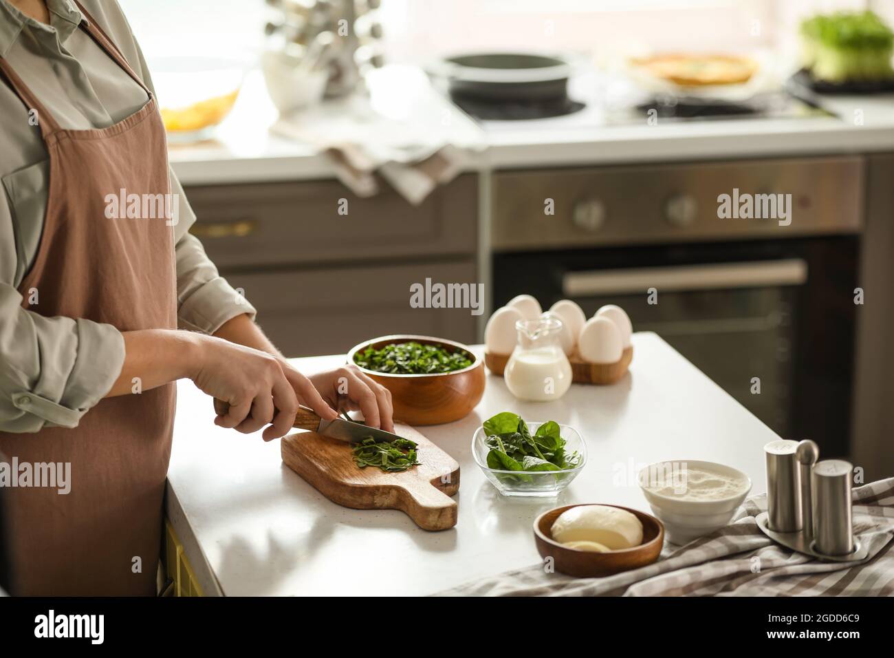 Woman cutting spinach for tart in kitchen Stock Photo - Alamy