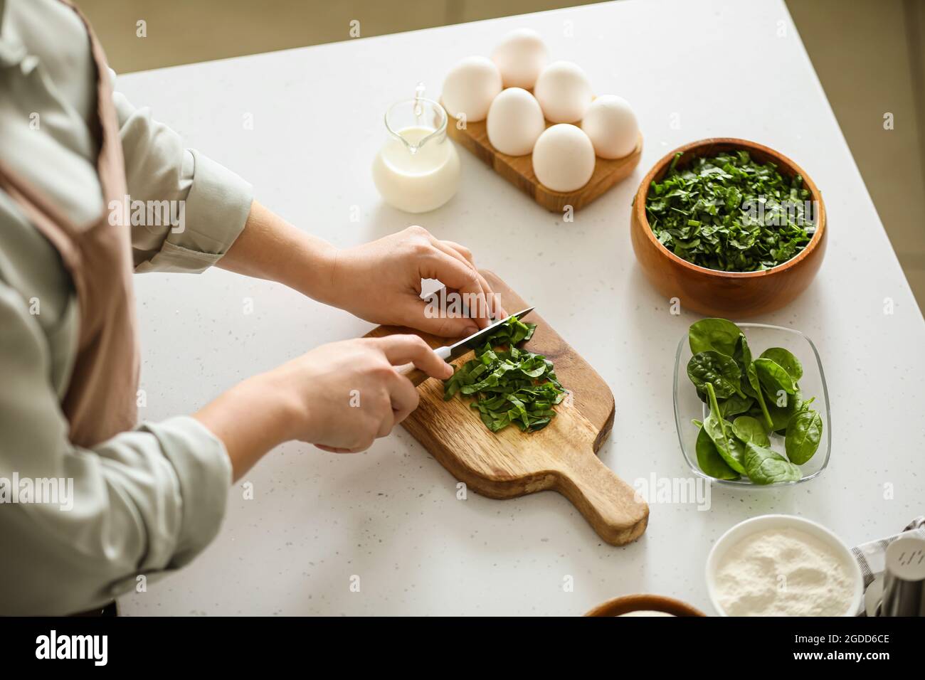 Woman cutting spinach for tart in kitchen Stock Photo - Alamy