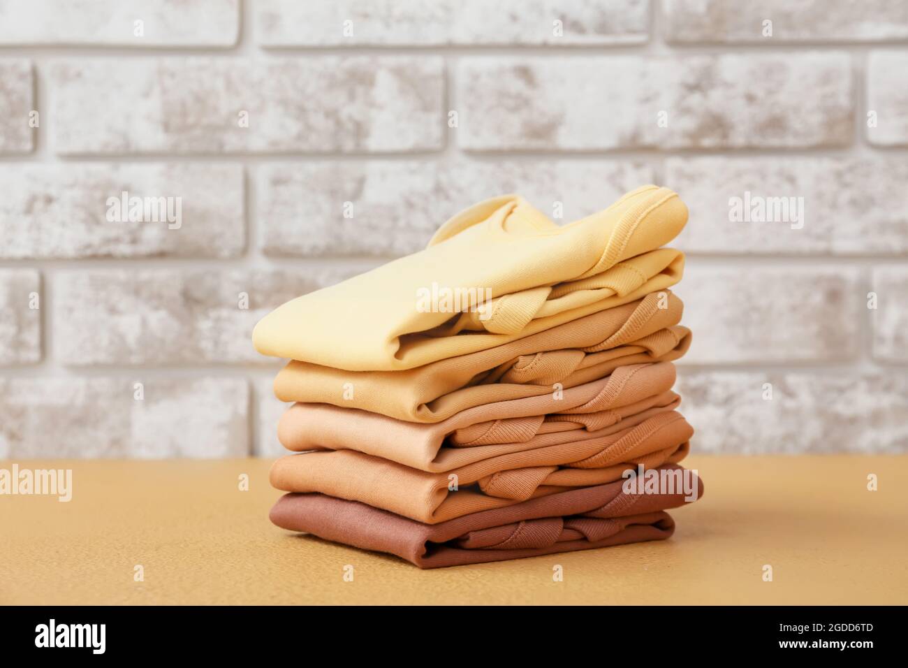 Stack of baby clothes on table against brick wall Stock Photo - Alamy